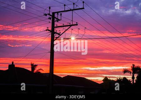 9 January 2026 A telegraph pole silhouetted against a red and pink ...