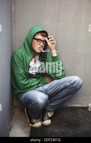Depressed young man smoking in a tenement hovel Stock Photo - Alamy