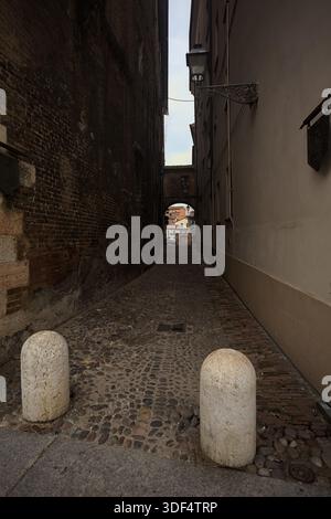 Narrow cobbled alley partially in the shade in an italian town seen ...