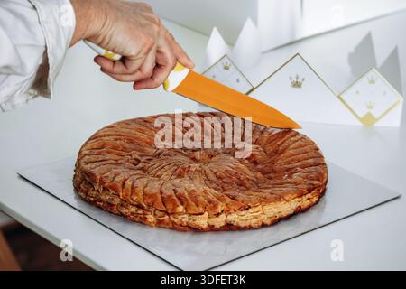A woman cutting a galette des rois, a traditional French pastry made of ...
