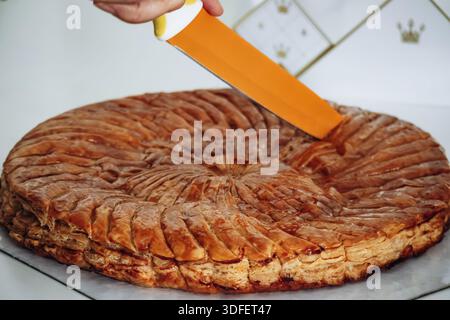 A woman cutting a galette des rois, a traditional French pastry made of ...