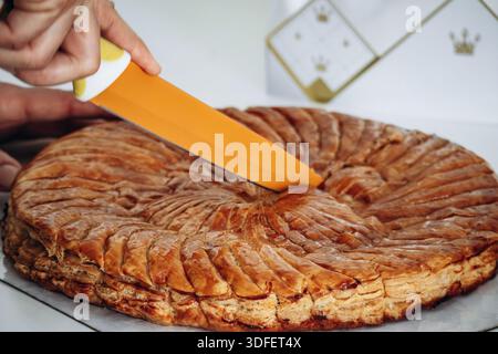 A woman cutting a galette des rois, a traditional French pastry made of ...