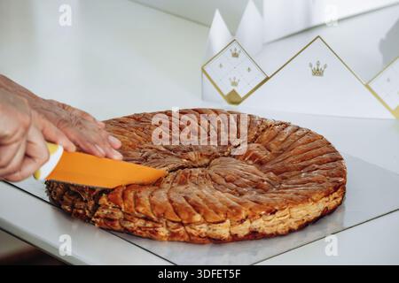 A woman cutting a galette des rois, a traditional French pastry made of ...