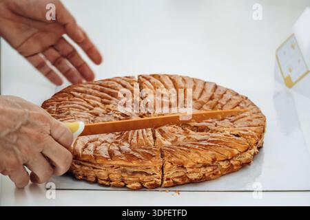 A woman cutting a galette des rois, a traditional French pastry made of ...