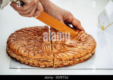 A woman cutting a galette des rois, a traditional French pastry made of ...