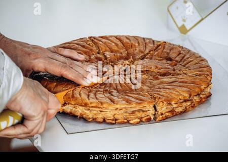 A woman cutting a galette des rois, a traditional French pastry made of ...