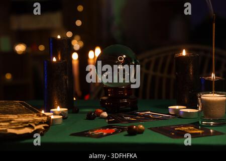 A fortune teller or oracle with divination items lights a candle ...