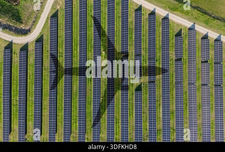Aerial view of an airplane shadow cast across a solar panel field ...