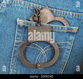 Police steel handcuffs in back jeans pocket close up Stock Photo - Alamy