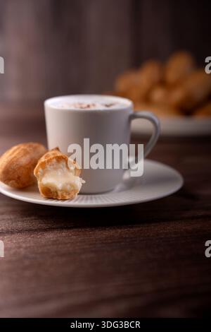 White cup with a golden handle, saucer and spoon, filled with black ...