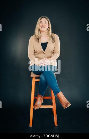 Blonde woman in denim attire smiling while listening music in retro ...