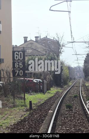 Railroad track with a sign by its edge and pillars with overhead ...