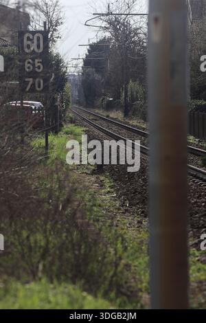 Railroad track with a sign by its edge and pillars with overhead ...