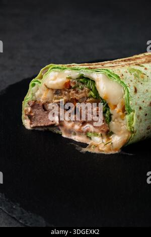 Wrap sandwich sliced in half showing ham cheese lettuce layers on dark ...