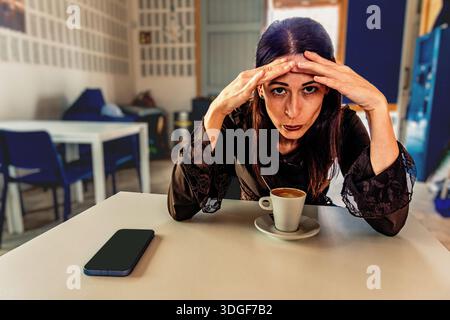 Woman feeling overwhelmed and having a headache while sitting at a park ...