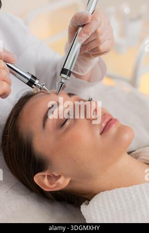 Cosmetologist doctor makes woman micro currents face forehead therapy ...