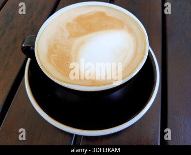 Cappuccino with frothy foam, yellow coffee cup top view is on the ...