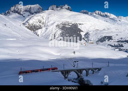 Bright red railway bridge crossing a river valley surrounded by fresh ...
