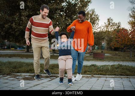 Diverse family playing outdoors in autumn park with child Stock Photo ...