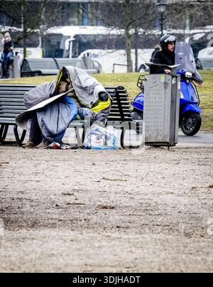 THE HAGUE - A man sits in a blanket on a bench outside in winter ROBIN ...