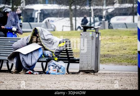 THE HAGUE - A man sits in a blanket on a bench outside in winter ROBIN ...