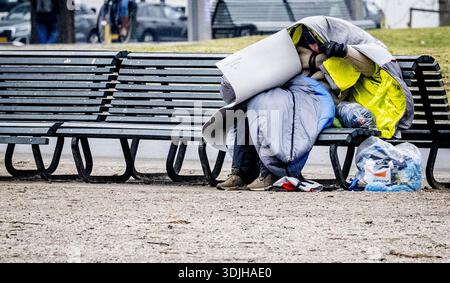 THE HAGUE - A man sits in a blanket on a bench outside in winter ROBIN ...