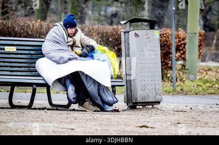 THE HAGUE - A man sits in a blanket on a bench outside in winter ROBIN ...
