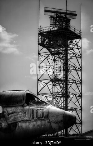 Aviation radar tower with rotating antenna rising above green forest ...