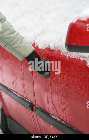 Person struggles to unlock a frozen car door handle covered with snow ...