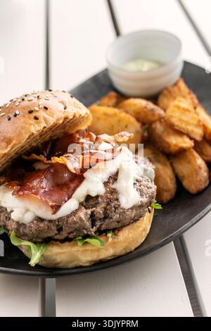 Gourmet wagyu beef burger wirh bacon, cheese and wedge fries on outdoor ...