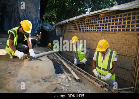 Rohingya volunteers work together to repair their shelter inside a ...