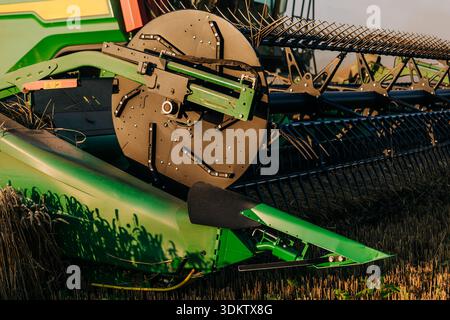 A combine harvester and a tractor are positioned in a harvested field ...