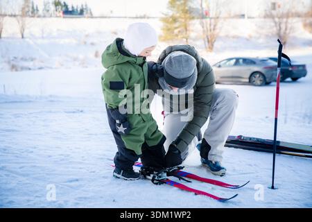 Father helping son with skis in Finnish forest. Active family winter ...