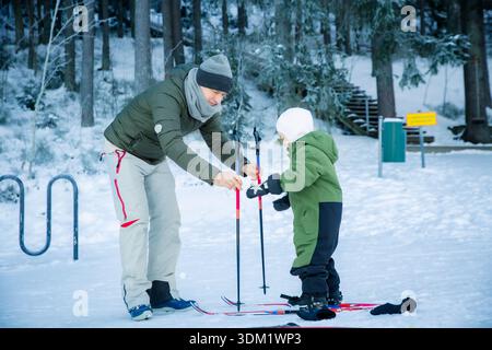 Father helping son with skis in Finnish forest. Active family winter ...