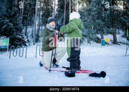 Father helping son with skis in Finnish forest. Active family winter ...
