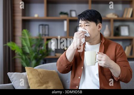 Asian man feeling unwell and resting on sofa at home Stock Photo - Alamy