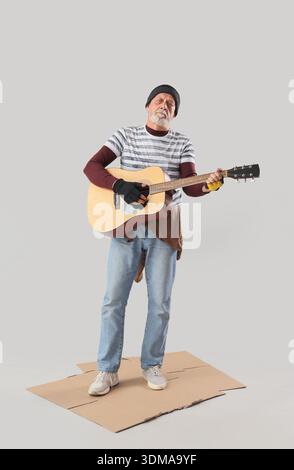 Mature homeless man playing guitar on street Stock Photo - Alamy