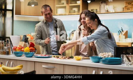 Family with tween girl singing and dancing around in the kitchen ...