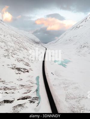 Aerial shot of a road through the snow-covered forest Stock Photo - Alamy
