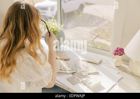 Female interior designer with fabric samples working at table in office ...