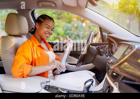 Woman fastening her seatbelt inside a modern vehicle, prioritizing road ...