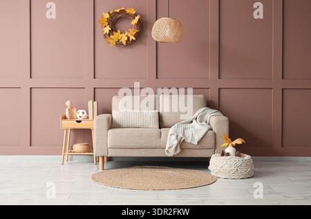 Comfortable sofa, table, pouf and autumn decor in interior of living ...