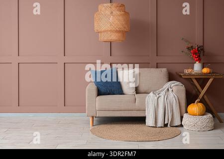 Comfortable sofa, table, pouf and autumn decor in interior of living ...