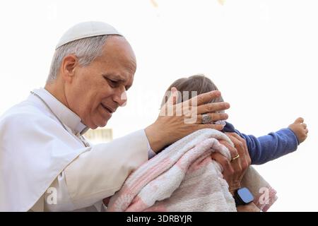 Pope Leo XIV caresses a baby as he arrives at the Pavia's Cathedral ...