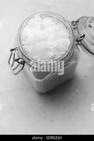 Magnesium chloride flakes are being stored in a glass jar with a metal ...