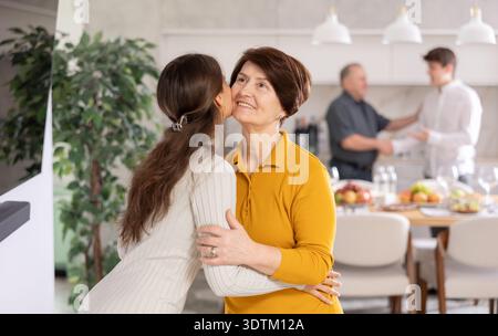 Happy mother meets her daughter, hugs and kisses her. In the background ...