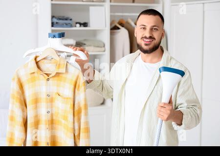 Young man with steamer in bedroom Stock Photo - Alamy