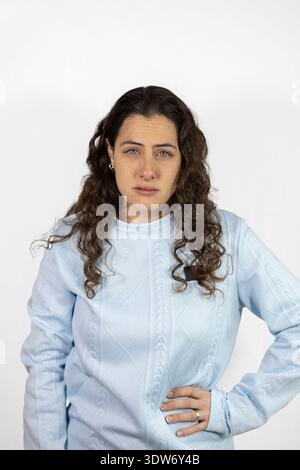 Young woman with curly hair expressing happiness against a blue ...