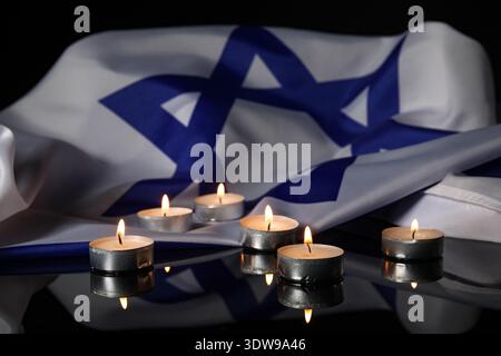 Burning candles and large flag of Israel on dark background. Holocaust ...