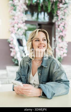 Smiling blonde woman wears denim outfit and poses confidently against a ...
